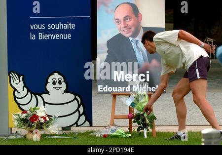A man places flowers at the base of a photograph of Edouard Michelin ...