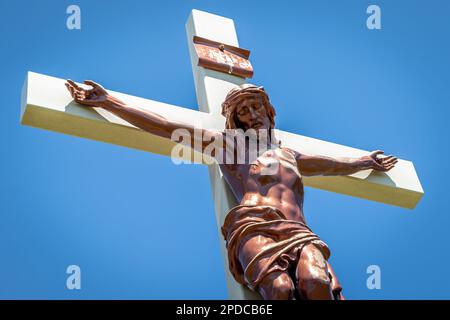 Gold colored statue at a cemetery of Jesus Christ hanging on the cross ...