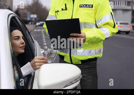 Woman giving bribe to police officer out of car window Stock Photo - Alamy