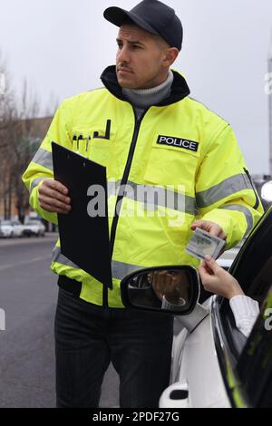 Woman giving bribe to police officer out of car window Stock Photo - Alamy