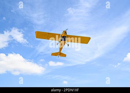 Single engine yellow propeller air plane flying at cloudy blue sky in a ...