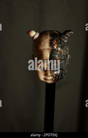 Damaged Dirty burnt Doll head on grey background Stock Photo - Alamy