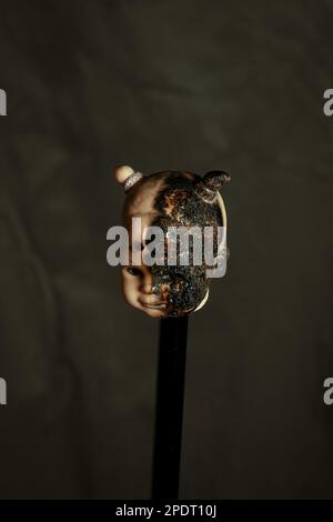 Damaged Dirty burnt Doll head on grey background Stock Photo - Alamy