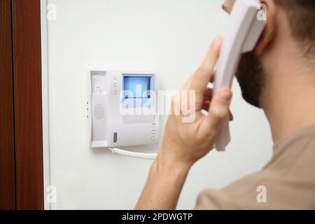 Man with handset answering intercom call indoors Stock Photo - Alamy