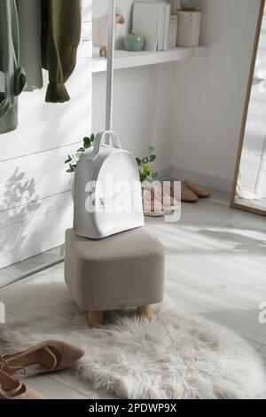 Stylish backpack on pouf in dressing room Stock Photo - Alamy