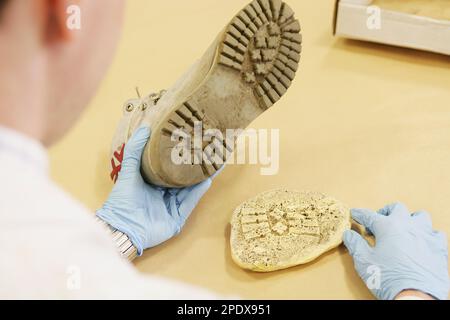 A forensic scientist matching a plaster cast of a boot print with real ...
