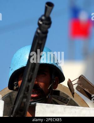 A U.N. peacekeeper from Pakistan stands guard as Haitians wait in line ...