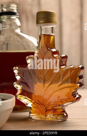 Bottles and bowl of maple syrup on color background Stock Photo - Alamy