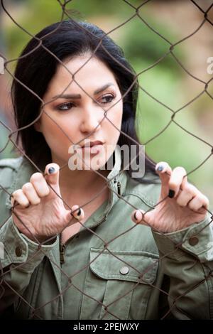 Serious woman holding chicken wire fence Stock Photo - Alamy