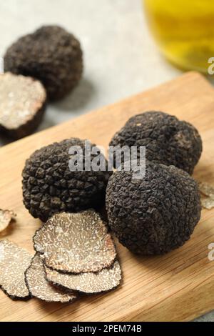 Whole and cut truffles on wooden table against black background ...