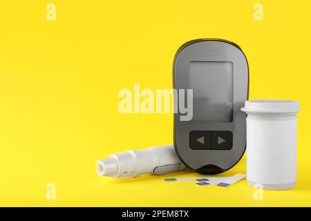 Digital glucometer, lancet pen, container and test strips on white ...