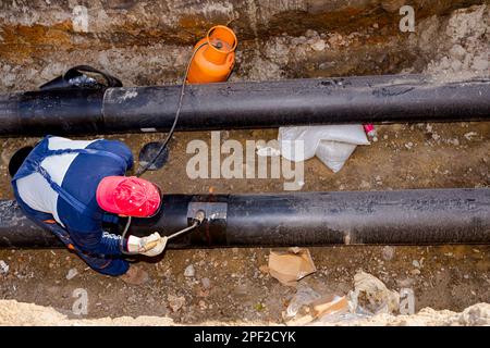 Rigger is gluing sheet of thermal protection on isolated pipeline using ...