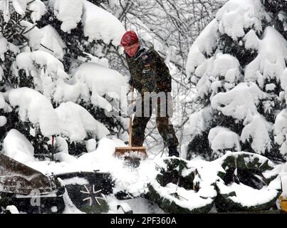 A German soldier shovels snow from the entrance area of his shelter ...