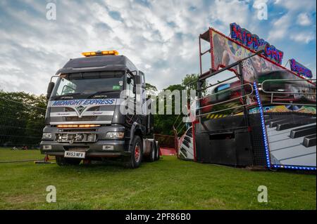 A Foden Alpha generator truck stands behind a fairground ride in a park ...