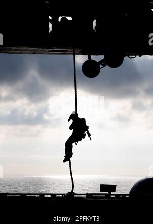 US Navy SEALs conduct a fast-rope exercise from the cargo door of an ...