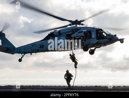 US Navy SEALs conduct a fast-rope exercise from the cargo door of an ...