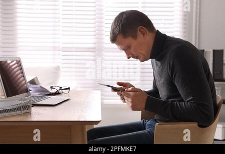 Man with bad posture using tablet while sitting on chair against grey ...
