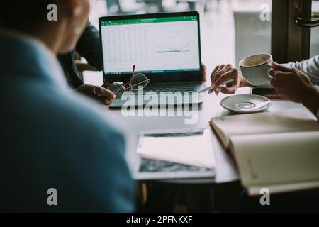 Three bussinesspeople looking at statistics and charts for their recent ...