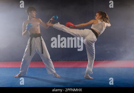 Two young and good looking karate friends doing the Ura Mawashi Geri ...