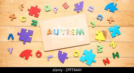 Word AUTISM with letters and puzzle pieces on wooden background Stock ...