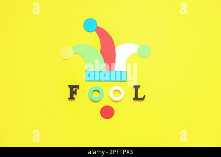 Paper hat with word FOOL on yellow background Stock Photo - Alamy