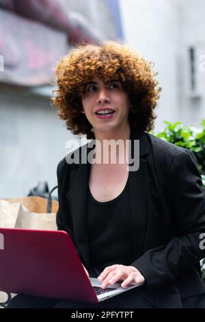 Non binary person using computer laptop doing money gesture with hands ...