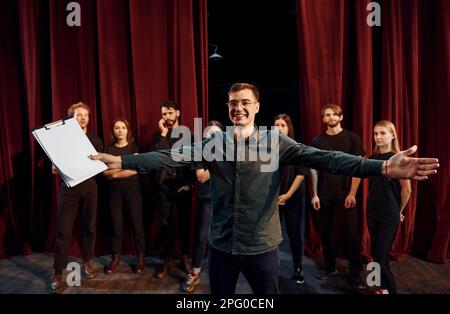 Man is practicing his role. Group of actors in dark colored clothes on ...