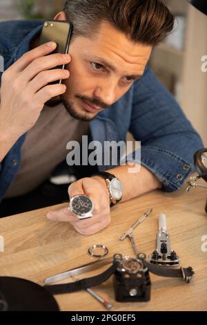 man on the phone while fixing a watch Stock Photo - Alamy