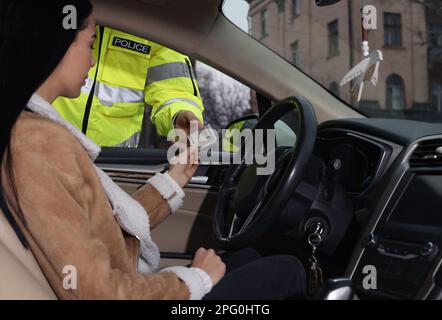 Woman giving bribe to police officer out of car window Stock Photo - Alamy