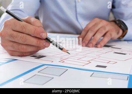 Professional cartographer working with cadastral map at table, closeup ...