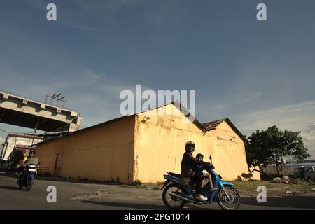 Motorists are photographed in a background of a warehouse building, in ...