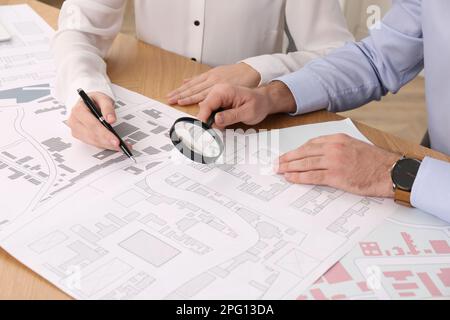 Professional cartographers working with cadastral map at table, closeup ...