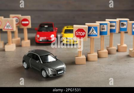 Many different miniature road signs and cars on wooden table. Driving ...