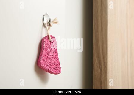 Pink pumice stone hanging on white wall, space for text Stock Photo - Alamy