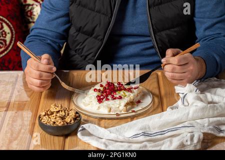 Gullac dessert. Ramadan dessert. Man eating gullac garnished with ...
