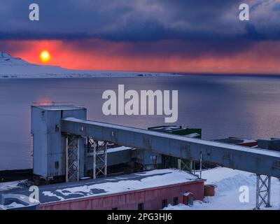 Sunset over the mine. Russian coal mining town Barentsburg at fjord ...