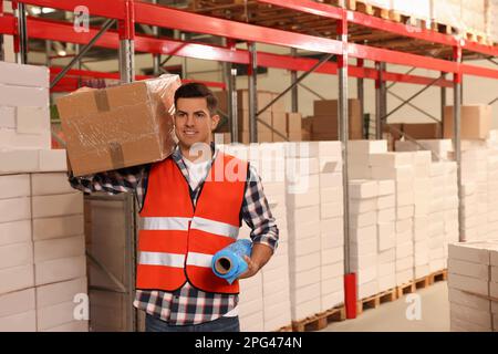 Worker with roll of stretch film and wrapped box in warehouse Stock ...