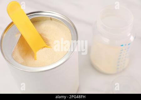 Blank can of powdered infant formula with feeding bottle and scoop on ...