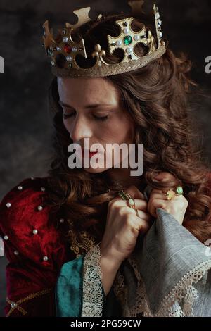 stressed medieval queen in red dress with crown having neck pain on ...