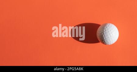 White dimple hockey ball and golf ball on orange color background ...