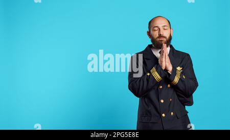 Spiritual aircrew captain praying to god in studio, being religious and ...