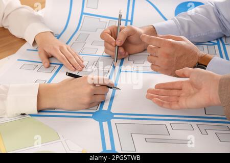 Professional cartographers working with cadastral map at table, closeup ...