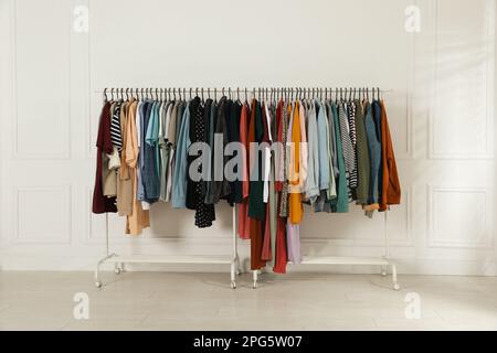 Racks with stylish clothes near white wall indoors, banner design. Fast ...