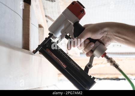 Cropped man hand hold pneumatic stapler, nail gun for wooden timber ...