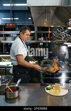 Chef throwing on air hot pasta in frying pan, cooking process Stock ...