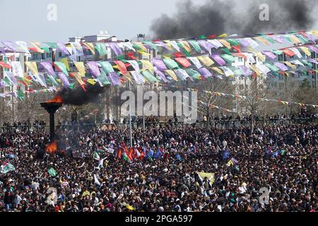 A nawroz fire is lit on a large torch with wood amid a crowd of ...