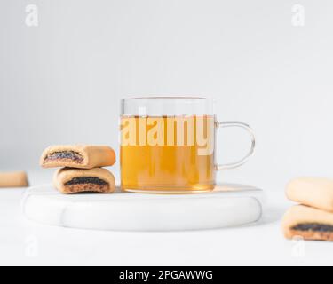 Glass cup of freshly brewed amber tea, dry ginger root with green ...