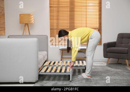 Young woman unfolding sofa into a bed in room. Modern interior Stock ...