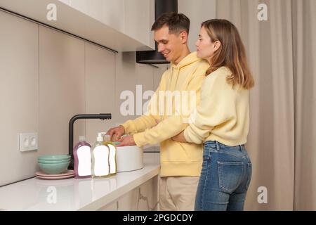 Couple washing the dishes using dishwashing liquid with blank label ...