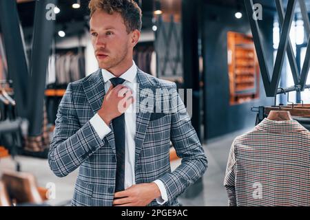 Tries on wear. Young guy in modern store with new clothes. Elegant ...